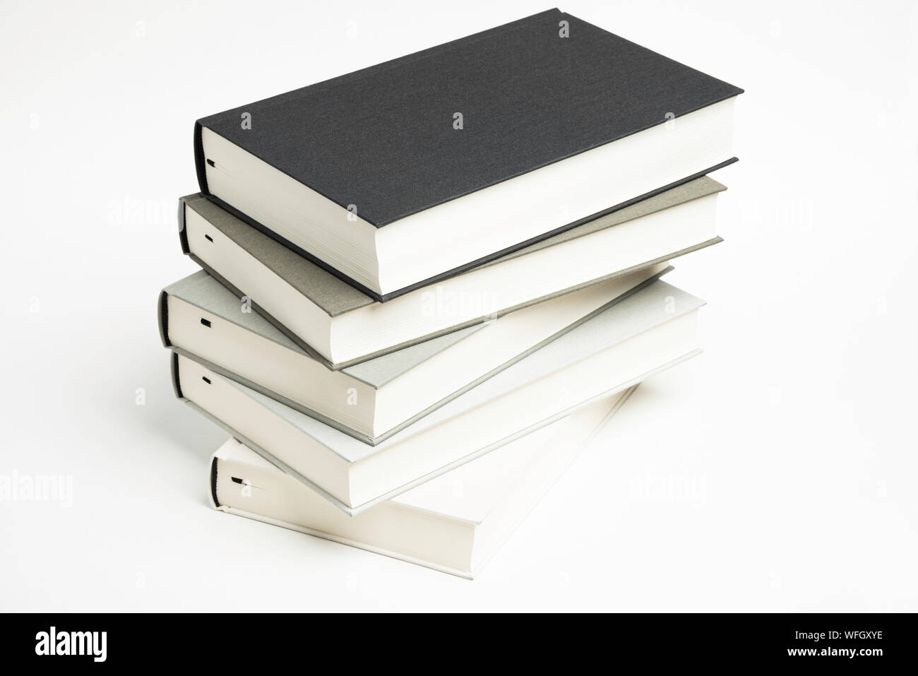 A disarrayed stack of five monochromatic cloth-bound books set on a ...