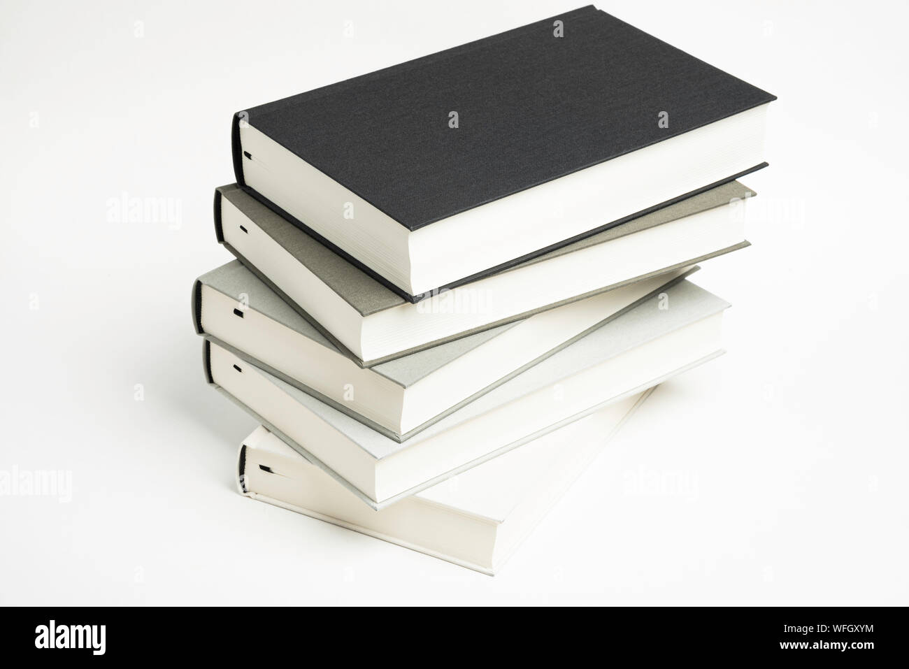A disarrayed stack of five monochromatic cloth-bound books set on a ...