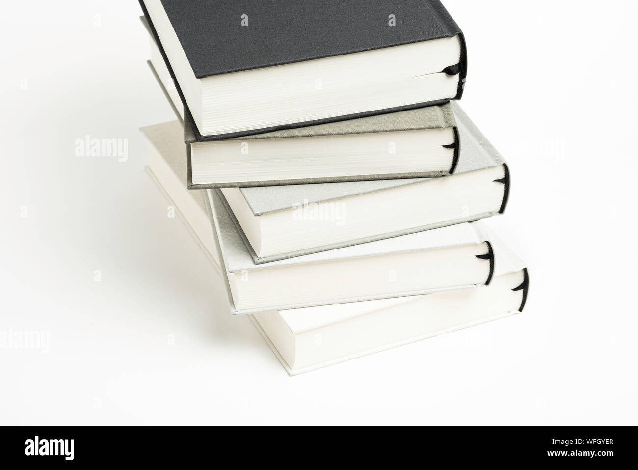 A disarrayed stack of five monochromatic cloth-bound books set on a ...