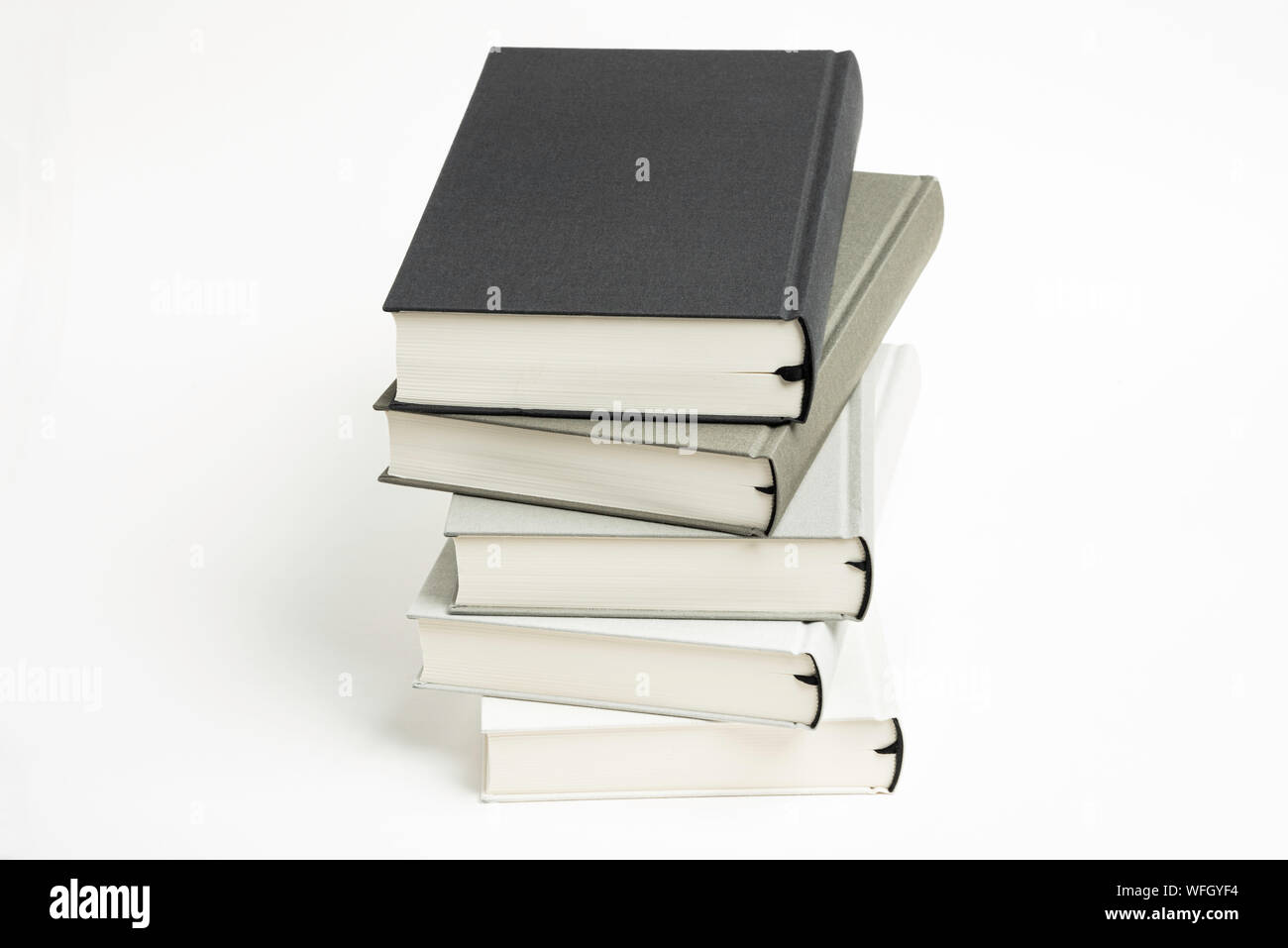 A disarrayed stack of five monochromatic cloth-bound books set on a ...