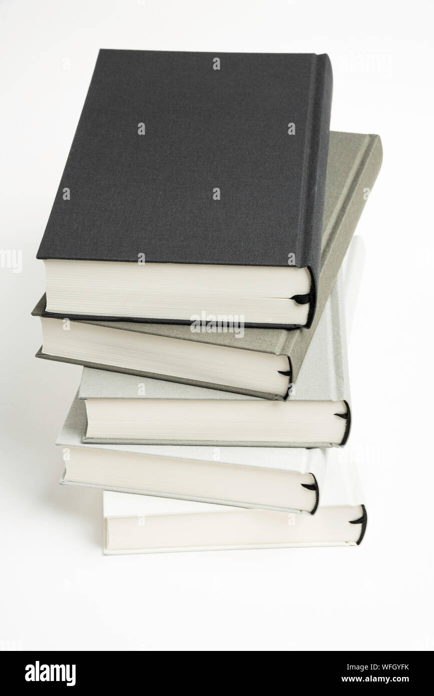 A disarrayed stack of five monochromatic cloth-bound books set on a ...