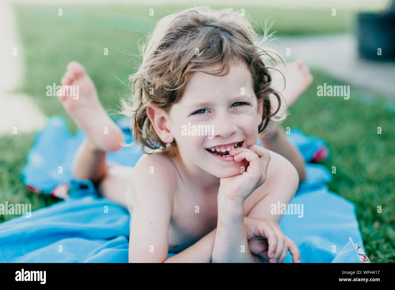 Smiling boy lying on a blanket in the garden Stock Photo - Alamy