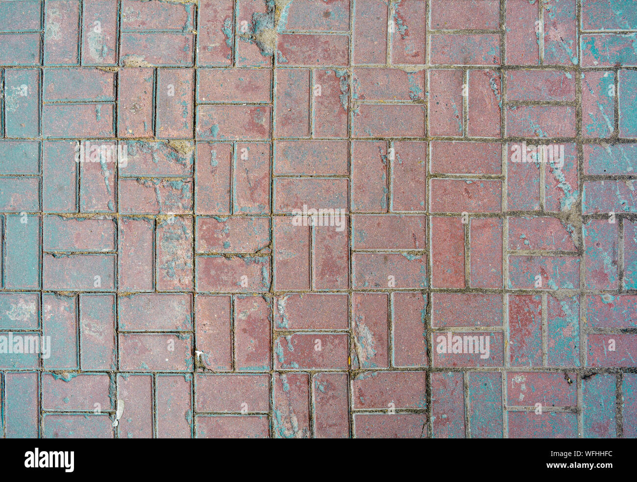 Grunge cracked red street tiles with blue paint. City street pavement ...