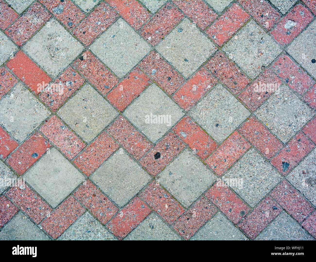 Red and gray road tiles on city street pavement with growing moss in ...