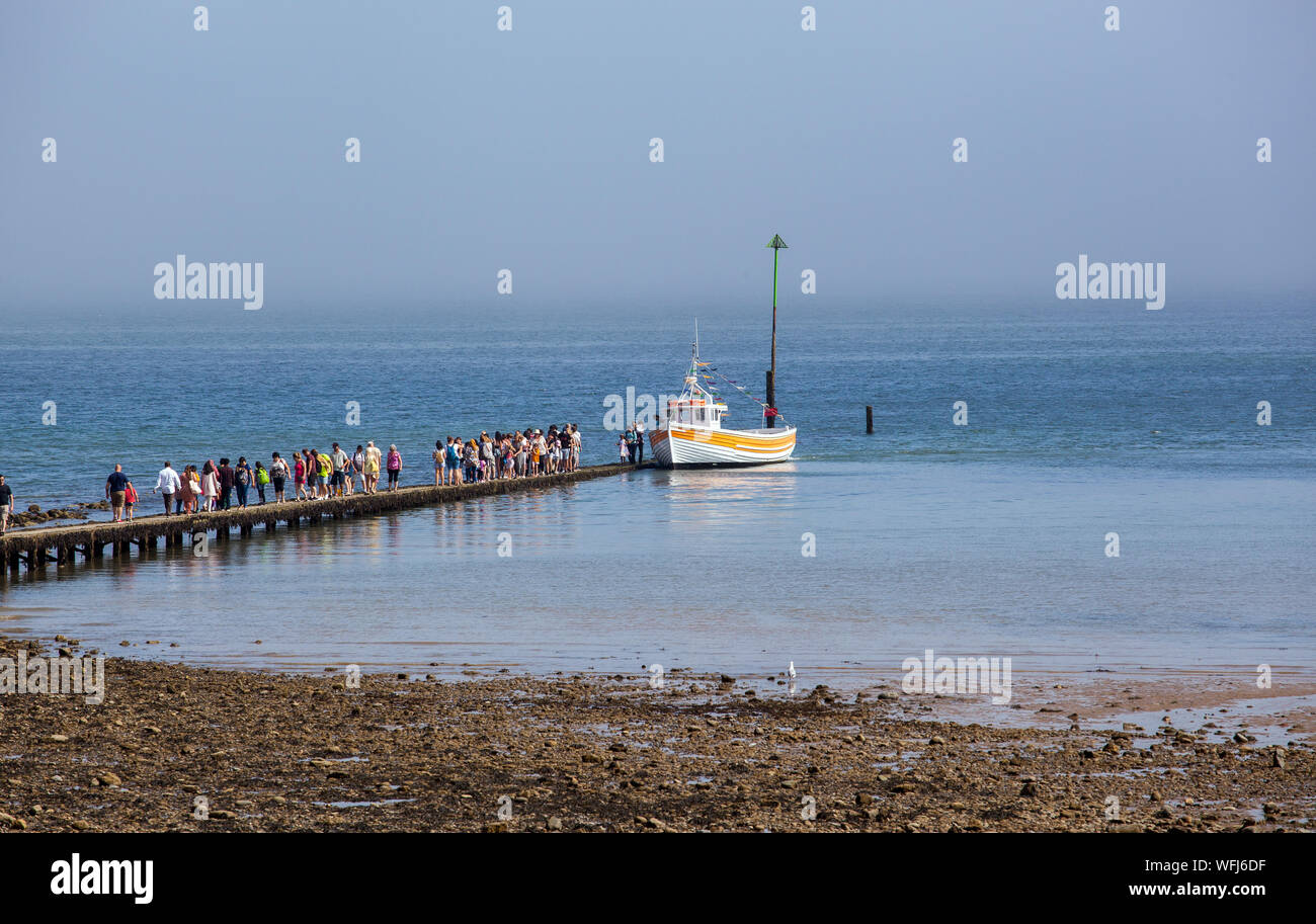 People holiday makers and tourists queuing on the jetty for a boat ride ...