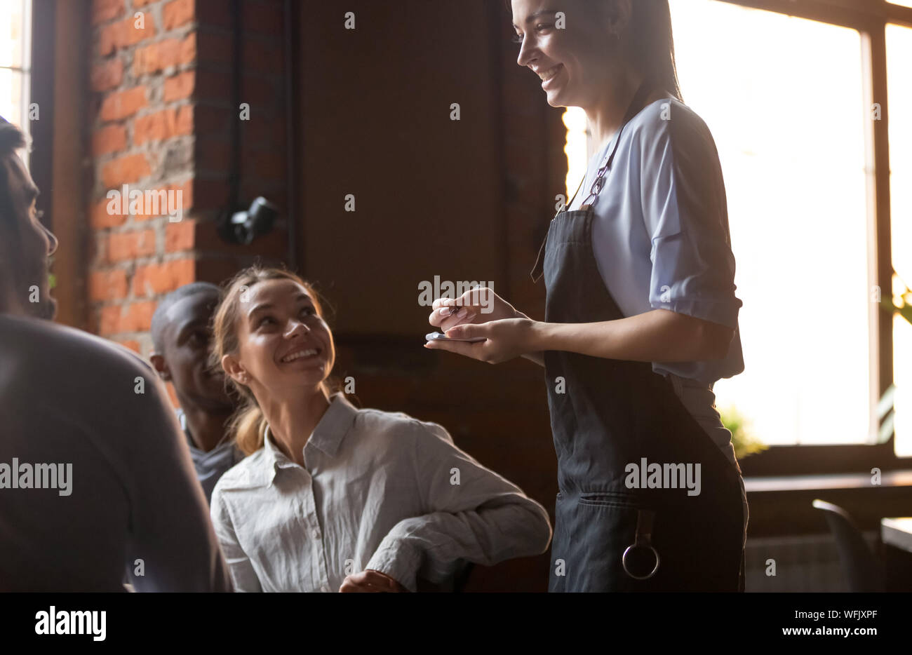 Happy waitress holding notepad taking order serving clients in cafe ...