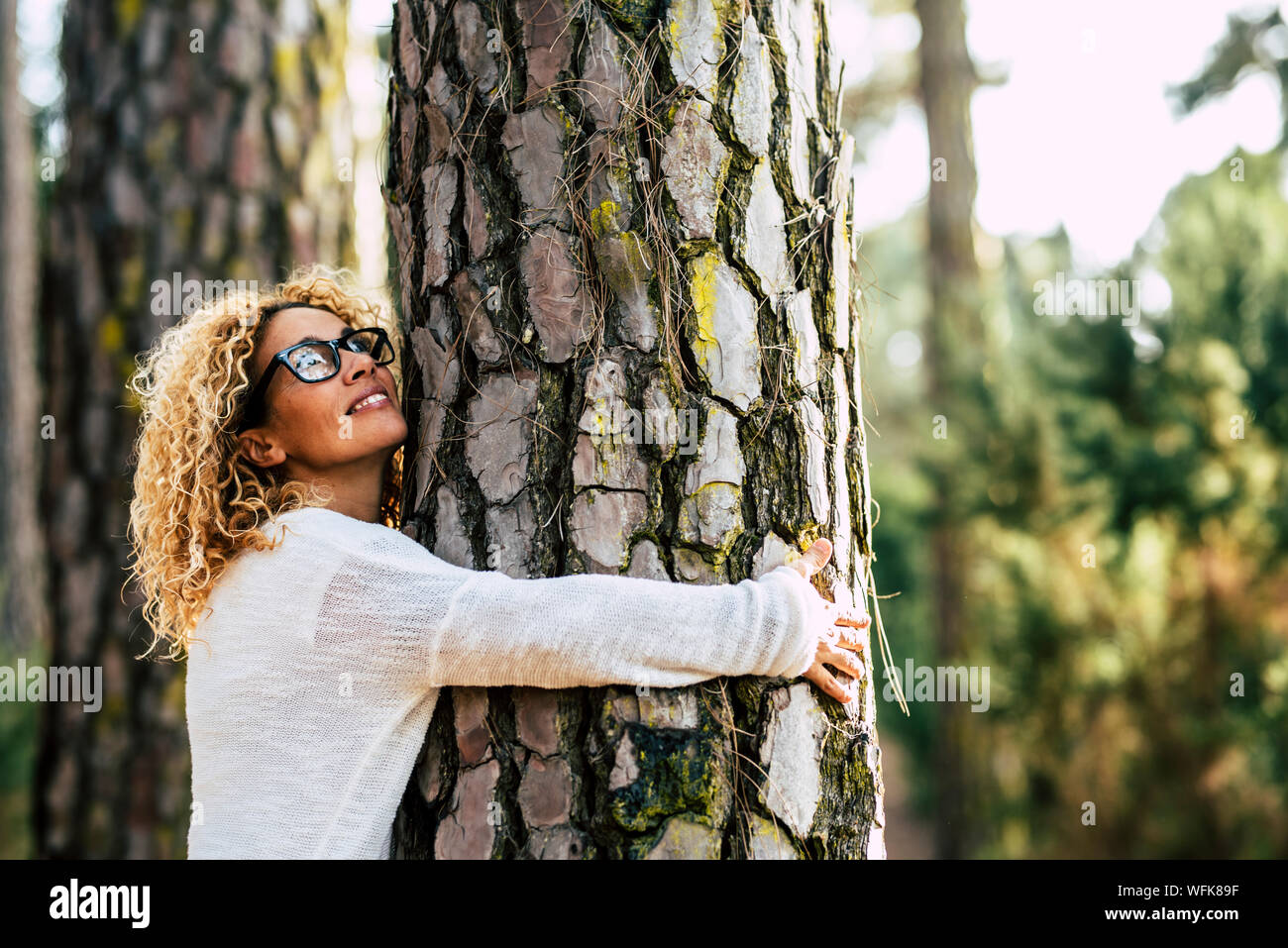 Happy beautiful woman love nature hugging a pine tree - no ...