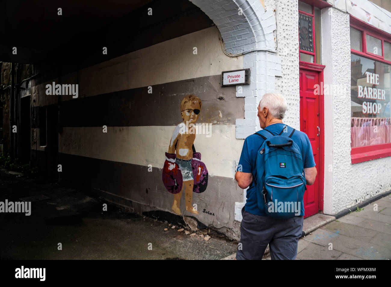 Confrontation. Senior man looking at the old wall painting of the boy ...