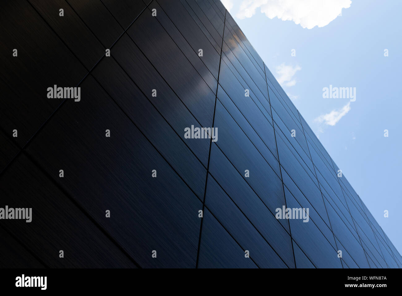 Ground view of dark tiled high building facade, sky background at ...