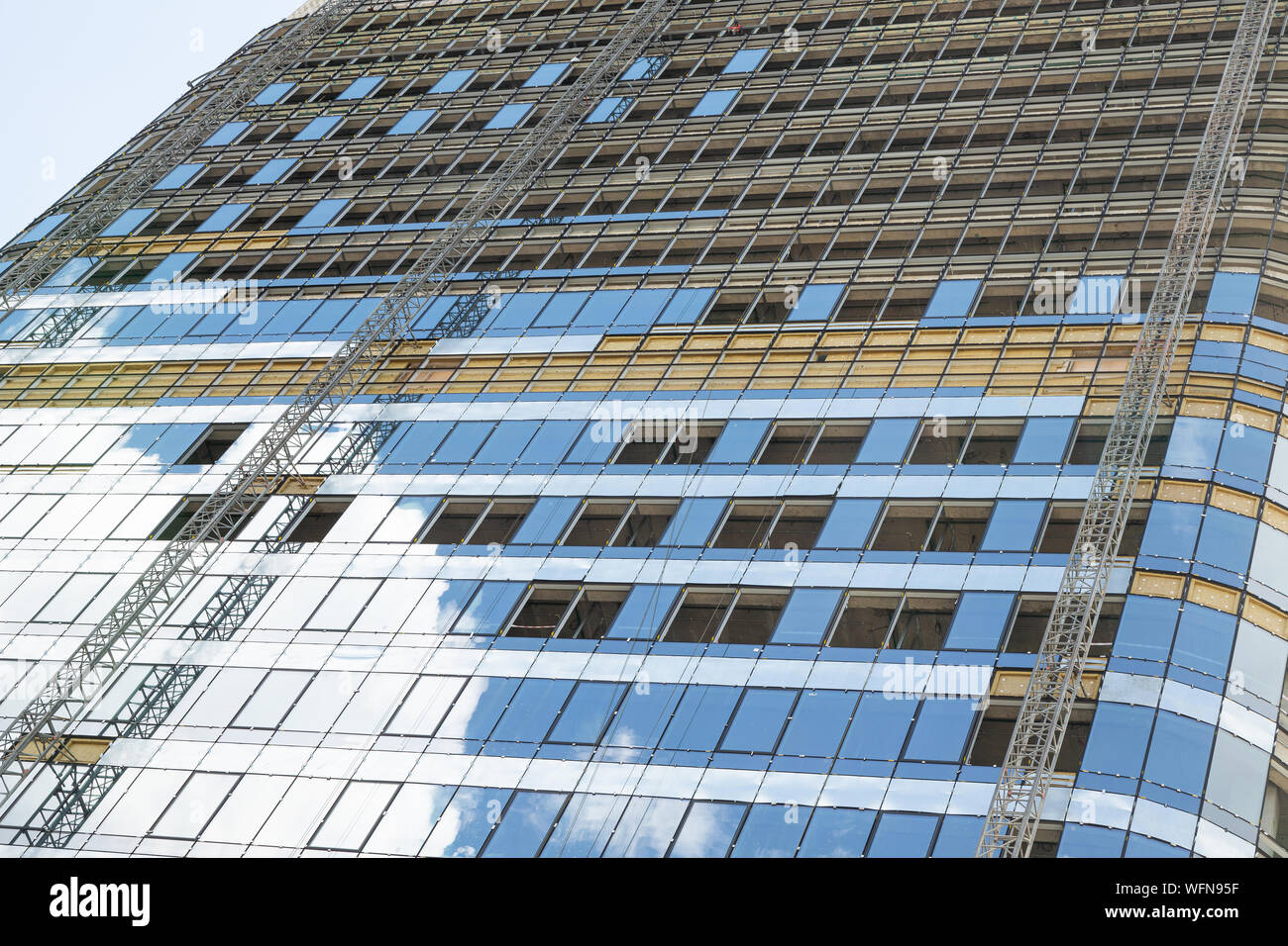 Low angle view of high modern glass building under renovation with sky ...