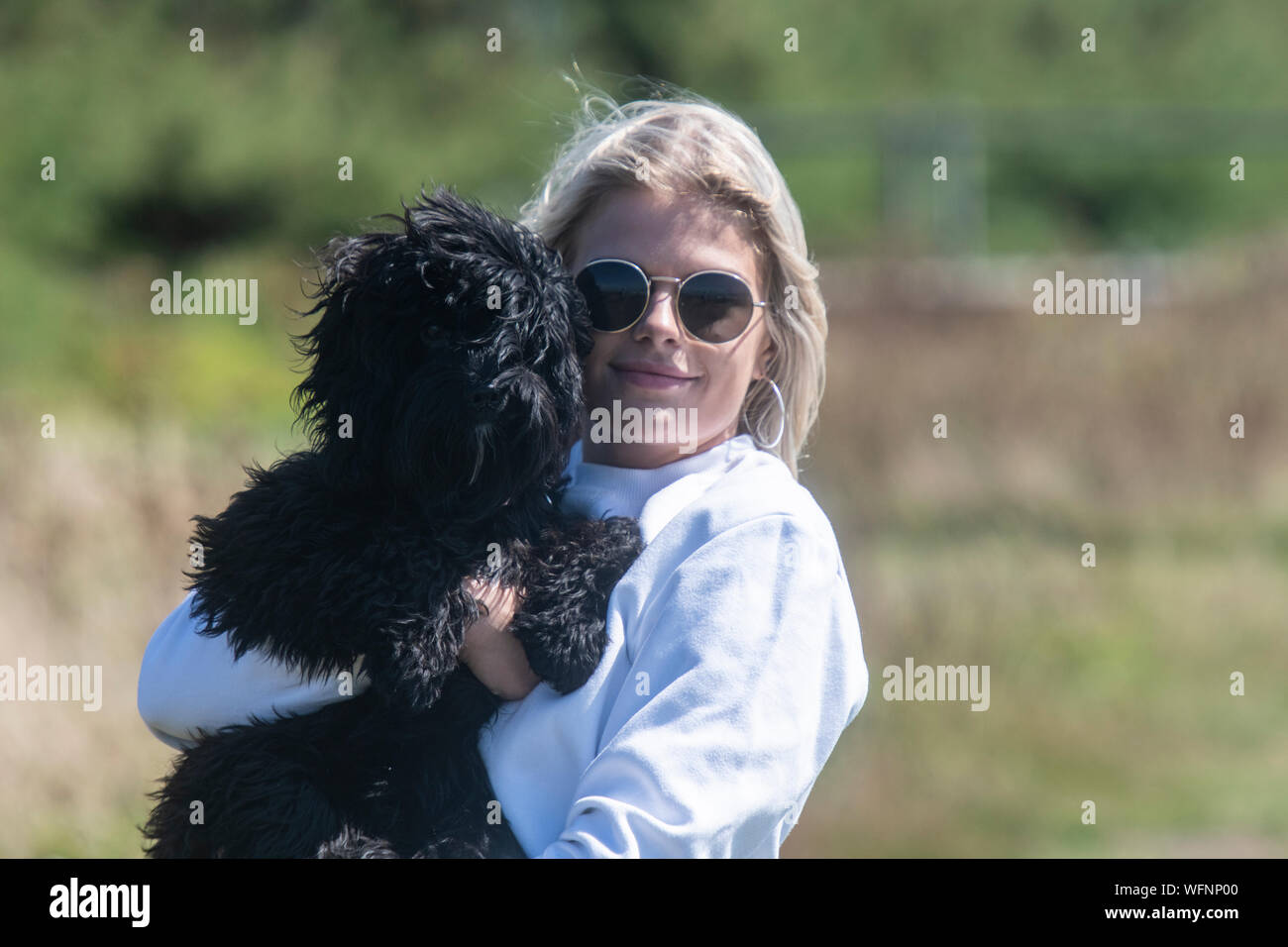 A young blonde girl wearing sunglasses holds her Cockapoo puppy Stock ...