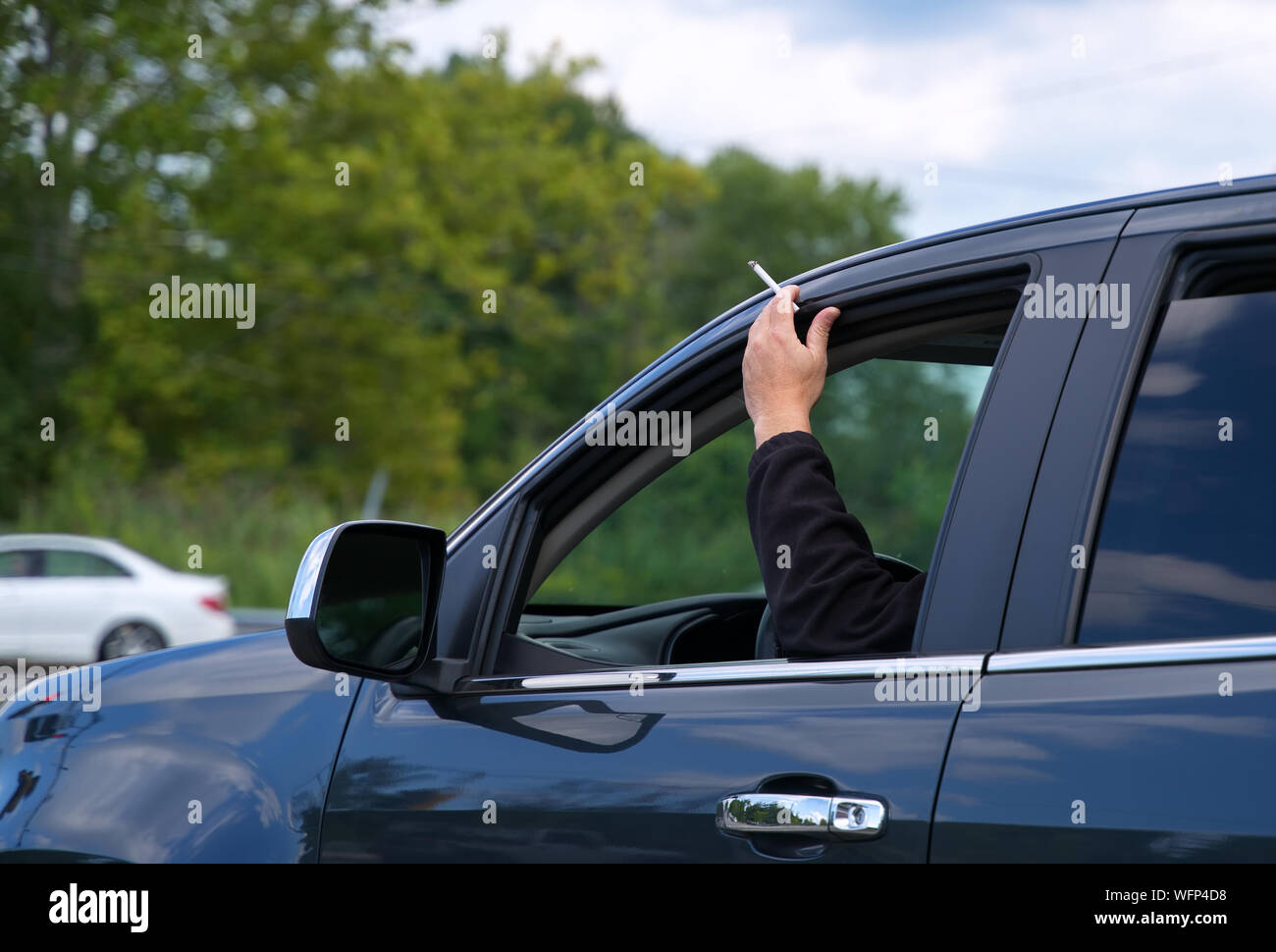Driver`s hand sticking out of car window holding cigarette while ...