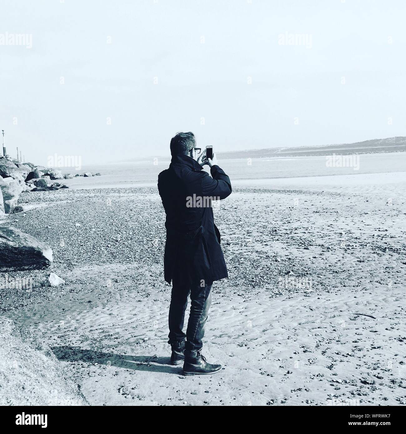 Rear View Of Man Taking Photo On Beach Stock Photo - Alamy