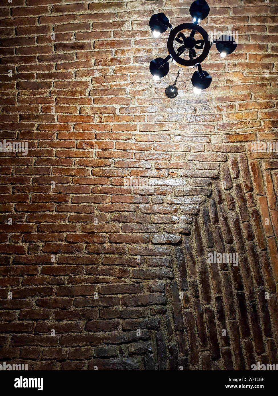 Antique chandelier style with modern lights. It hangs on a red brick ...