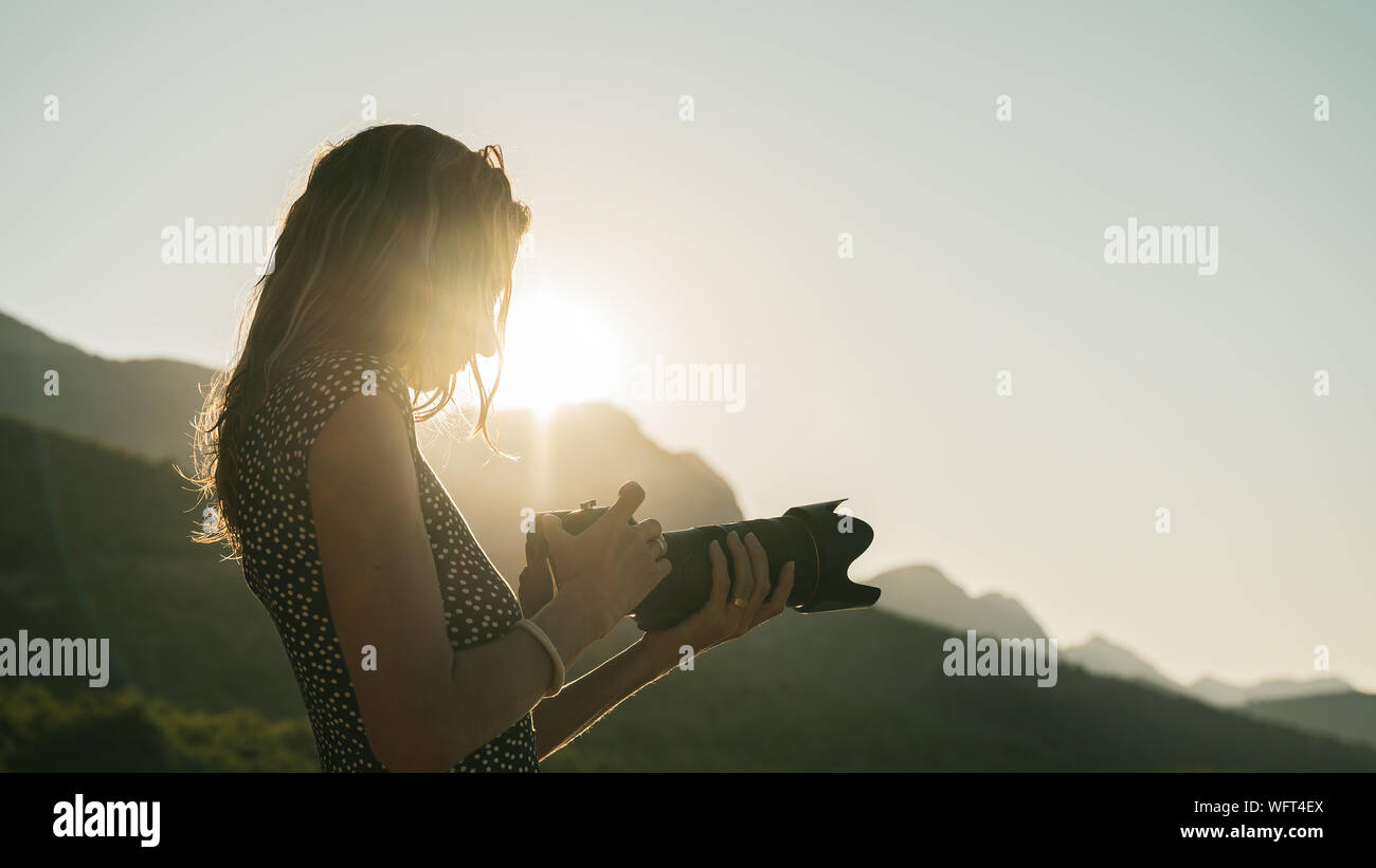 Young female photographer looking at her dslr camera adjusting the ...
