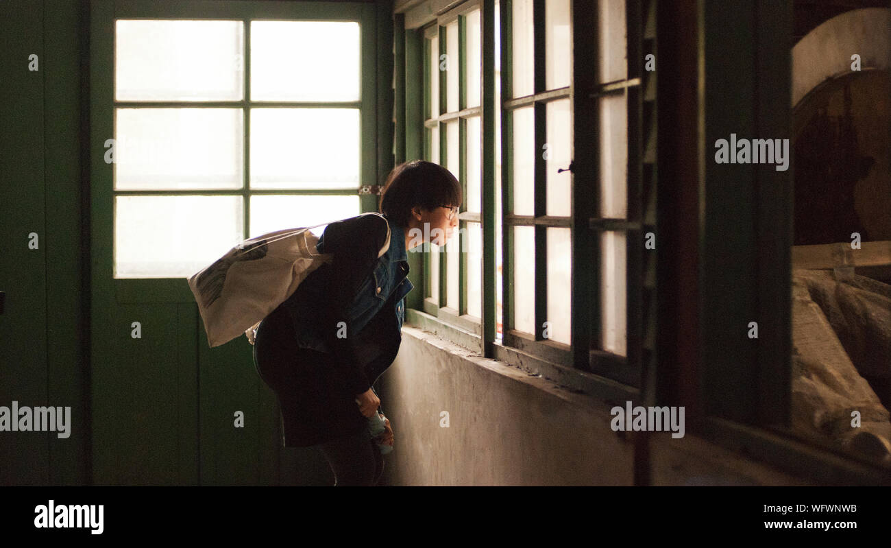 Young Woman Looking Through Window In House Stock Photo - Alamy