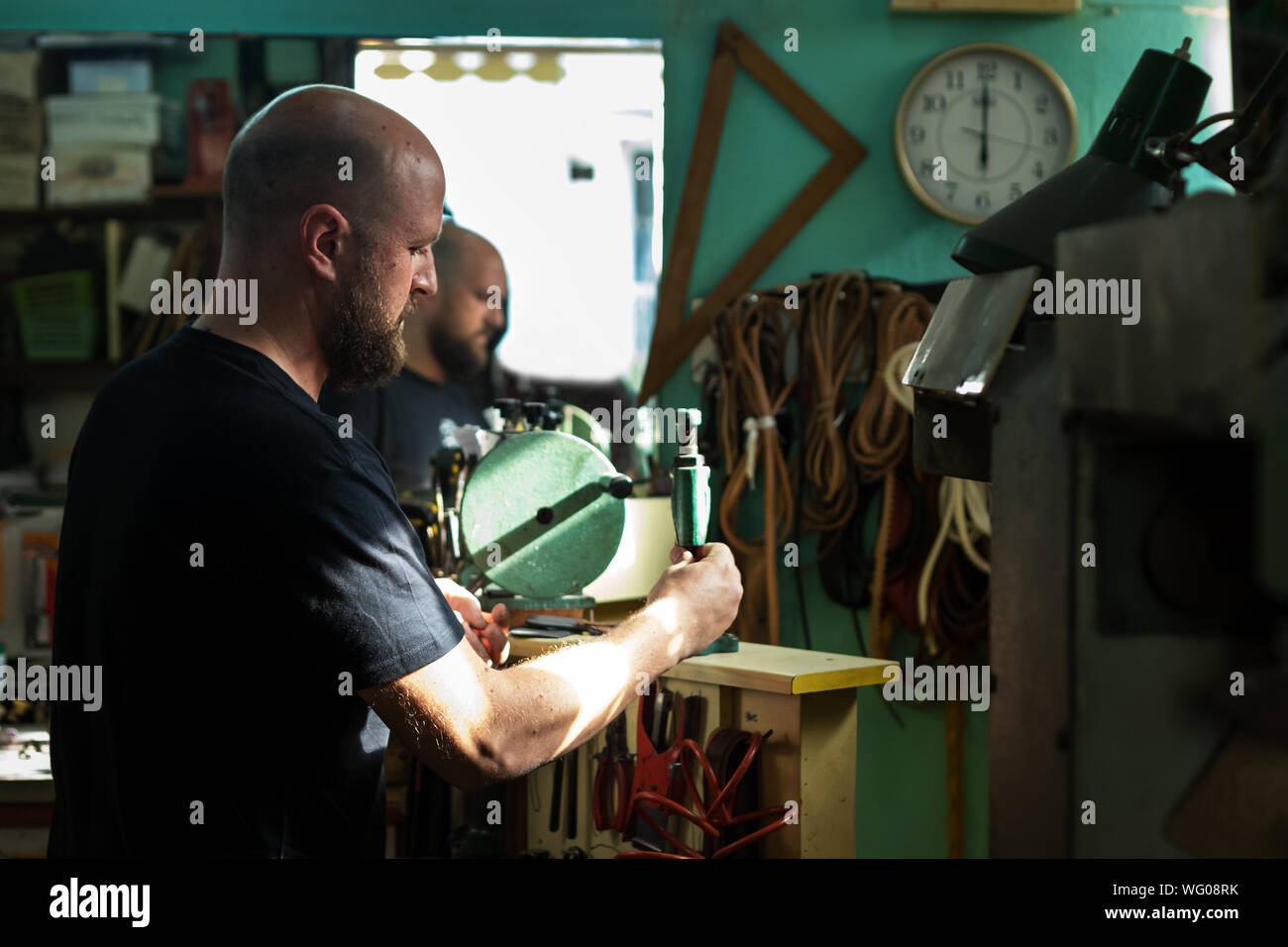 A male shoemaker riveting with an old rivet press machine at h.is ...