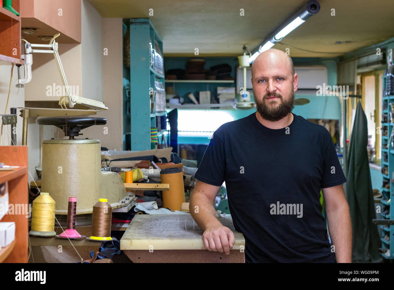Portrait of a shoemaker bald man with beard, posing standing at his ...