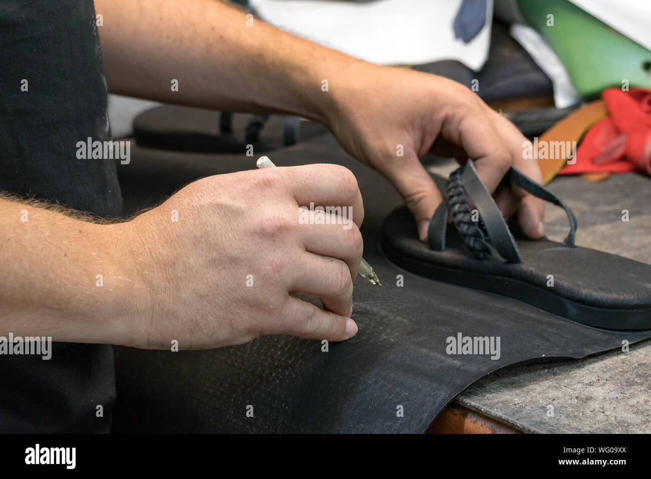 A male shoemaker hand drawing on a rubber sole to repair a sandal Stock ...