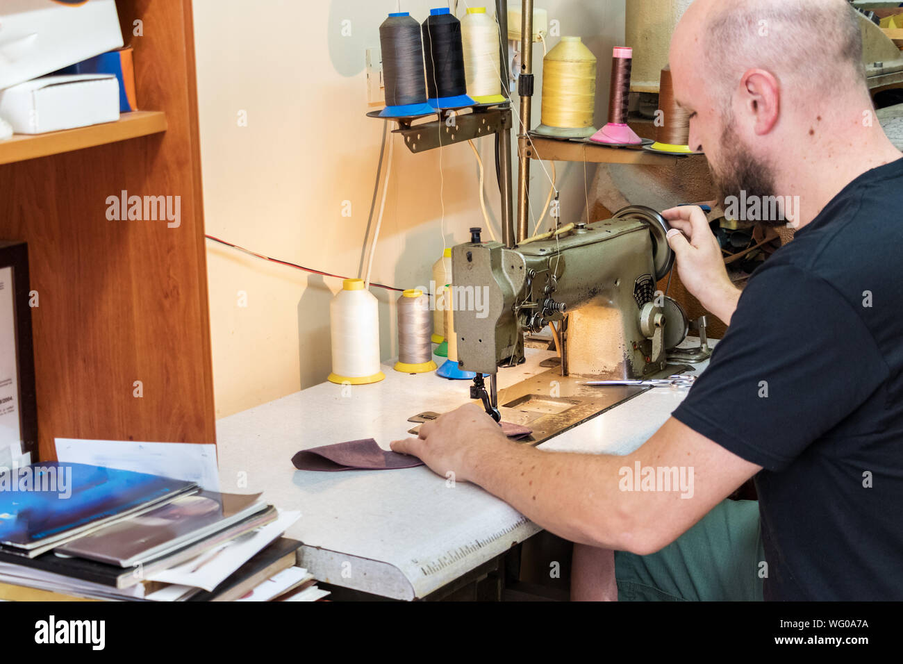 A male shoemaker sewing leather with an old sewing machine Stock Photo ...
