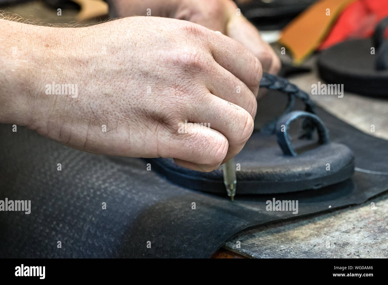 A male shoemaker hand drawing on a rubber sole to repair a sandal Stock ...