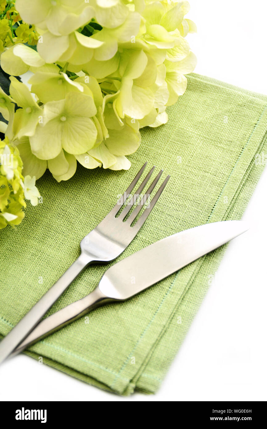 Smple informal place setting with green napkin, hydrangea flowers and ...