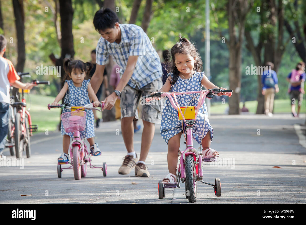 Full Length Of Sisters Riding Bicycles With Father On Road At Public ... Full Length Of Sisters Riding Bicycles With Father On Road At Public ...