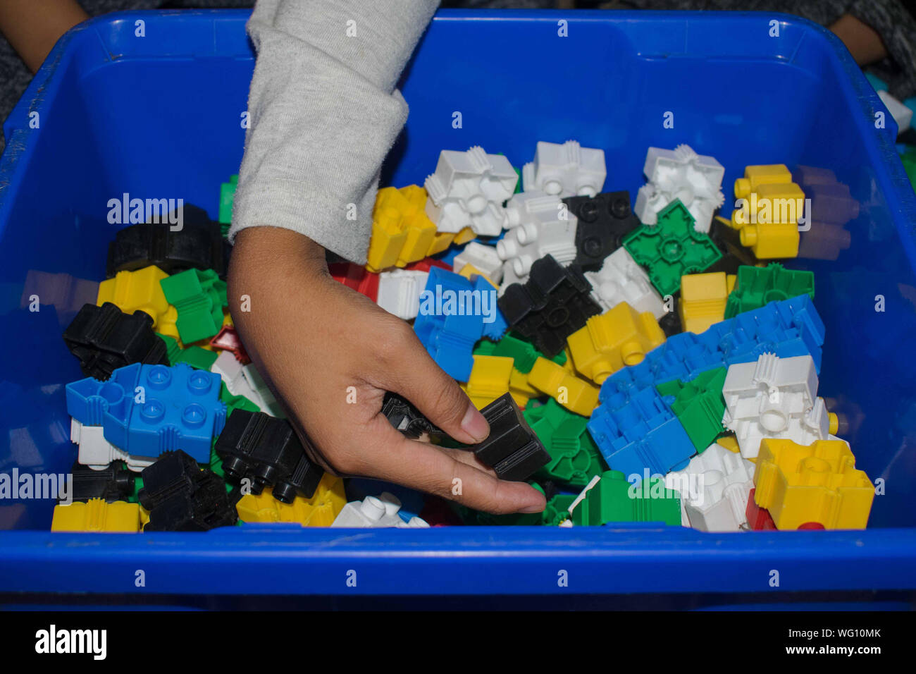 Hand of a child while choosing a lego peiece form a box full of lego ...
