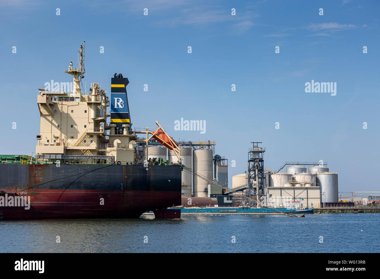 Large seafarer ship docked next to industrial storage facilities Stock ...
