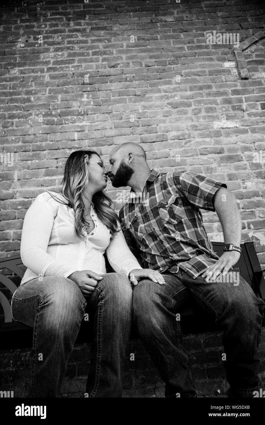 Affectionate young couple kissing brick wall hi-res stock photography ...