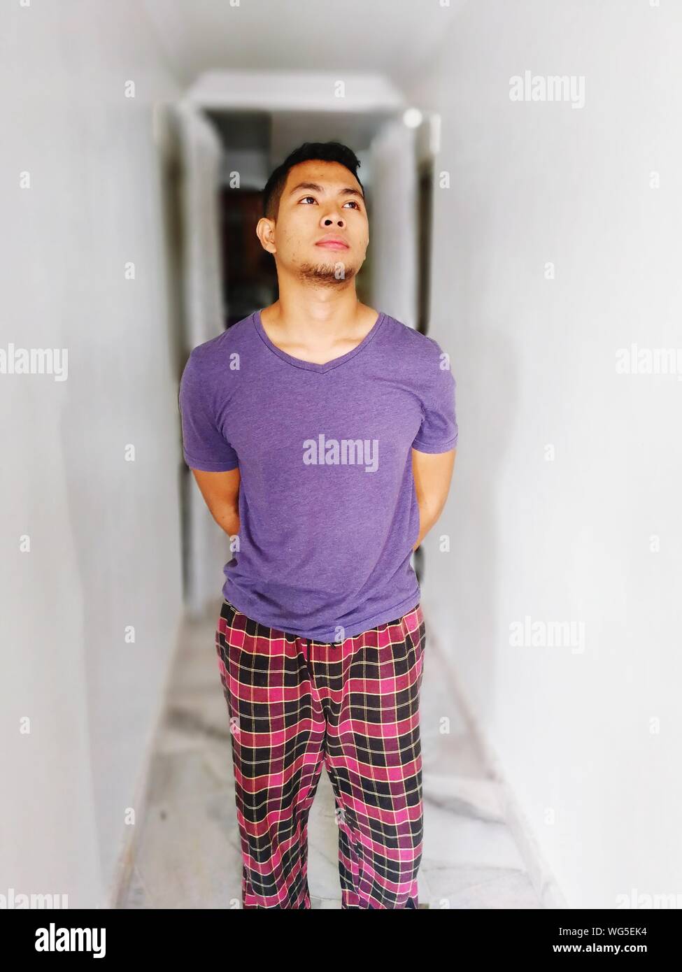 Young Man Looking Up While Standing In Corridor Stock Photo - Alamy