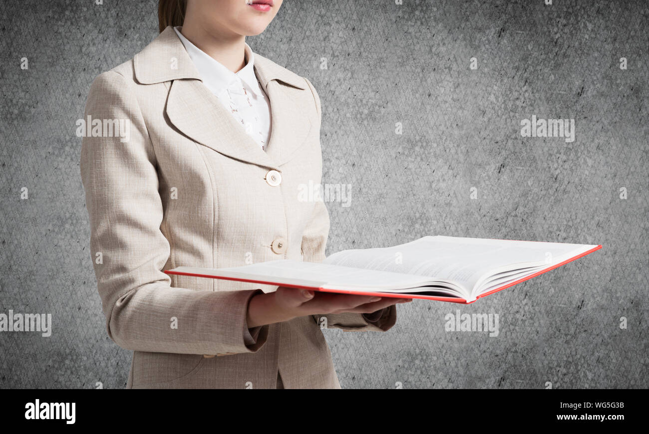 Business woman holding open book on background of grey wall. Business ...