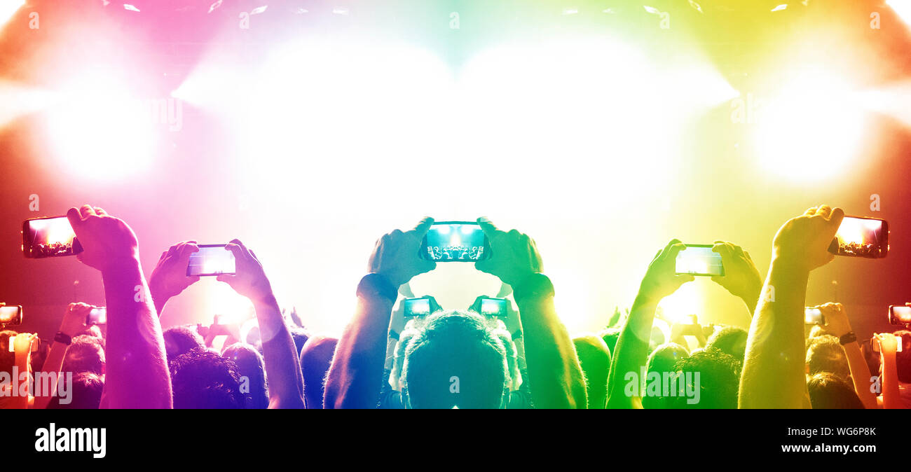 Concert crowd clapping in front of a bright stage Stock Photo - Alamy