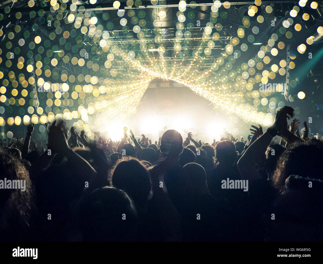 Concert crowd clapping in front of a bright stage Stock Photo - Alamy