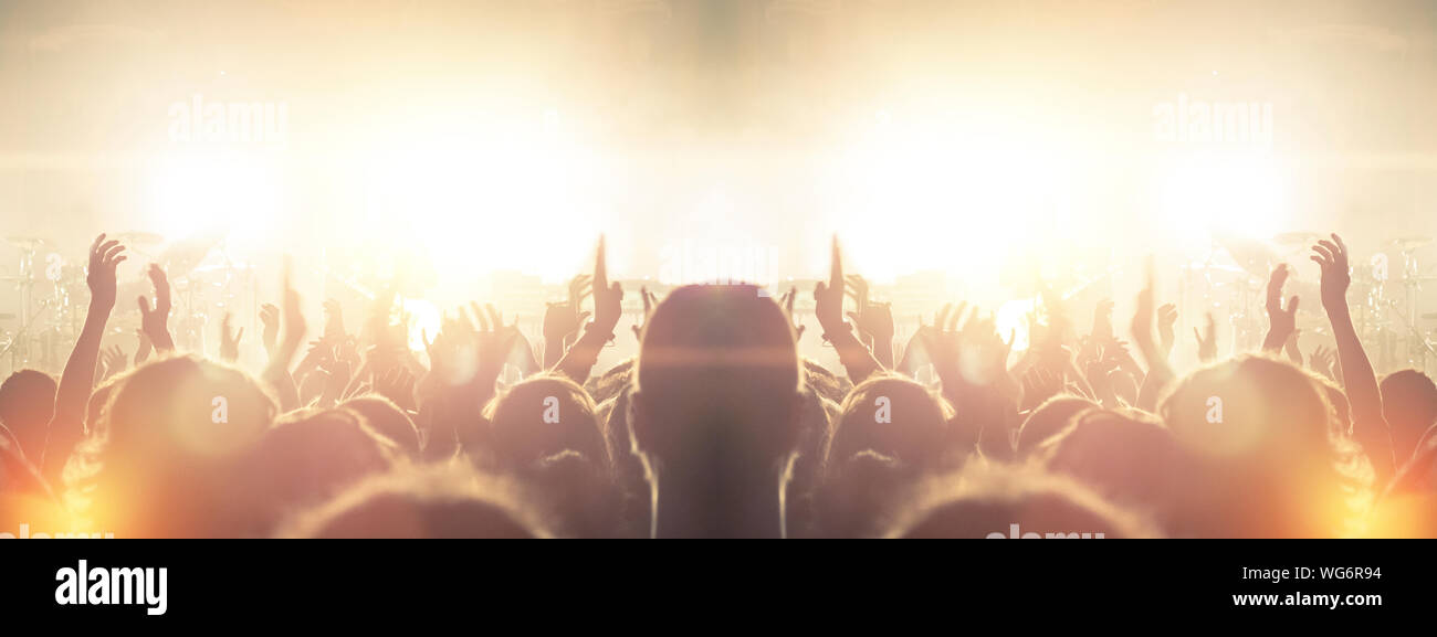 Concert crowd clapping in front of a bright stage Stock Photo - Alamy