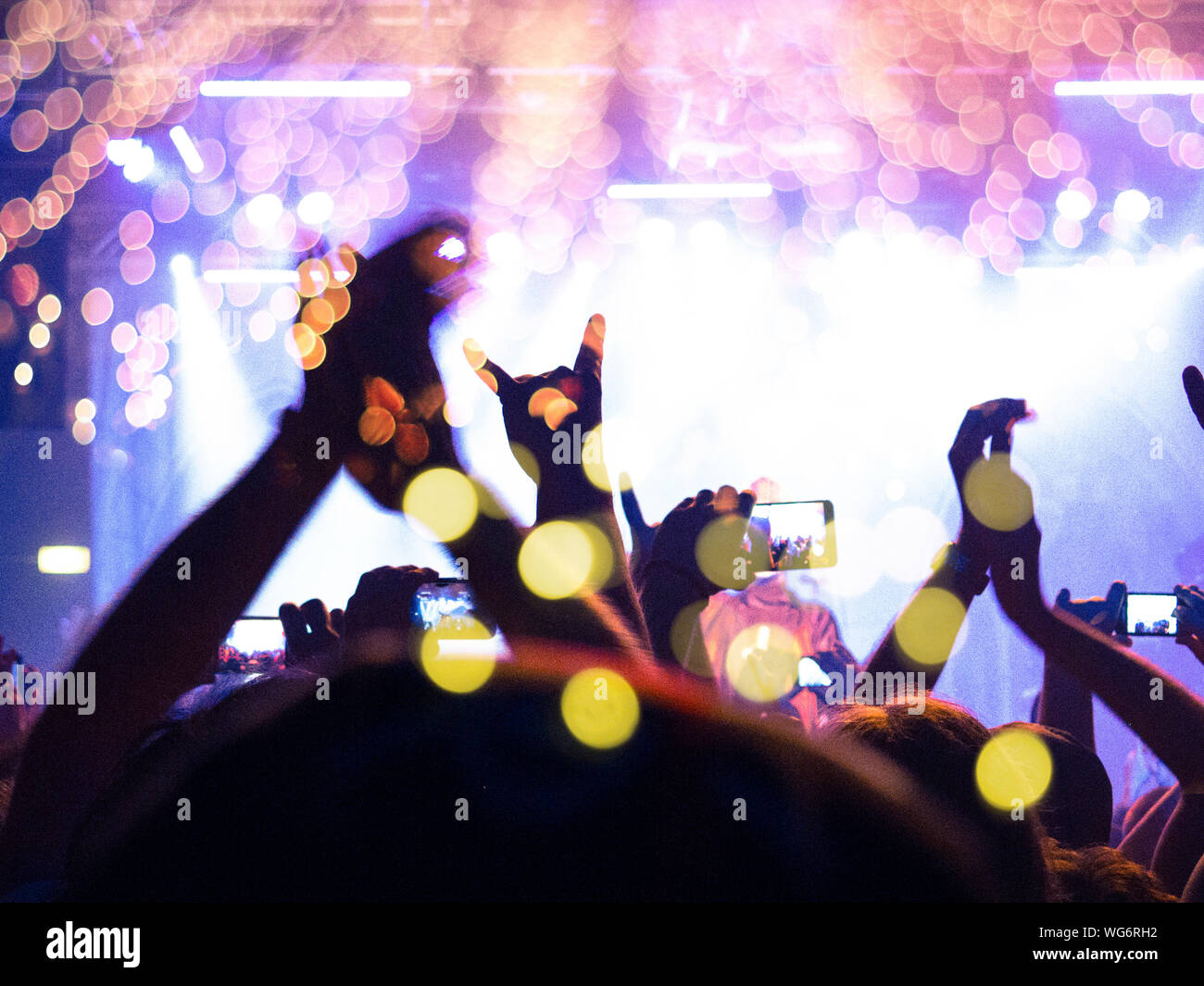 Concert crowd clapping in front of a bright stage Stock Photo - Alamy