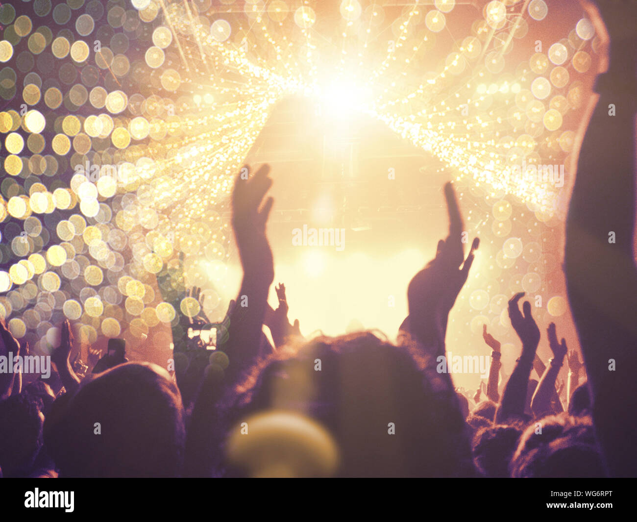 Concert crowd clapping in front of a bright stage Stock Photo - Alamy