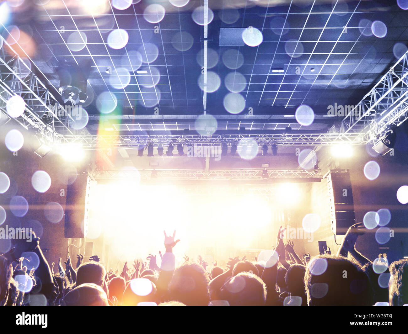 Concert crowd clapping in front of a bright stage Stock Photo - Alamy