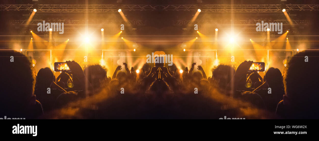 Concert crowd clapping in front of a bright stage Stock Photo - Alamy