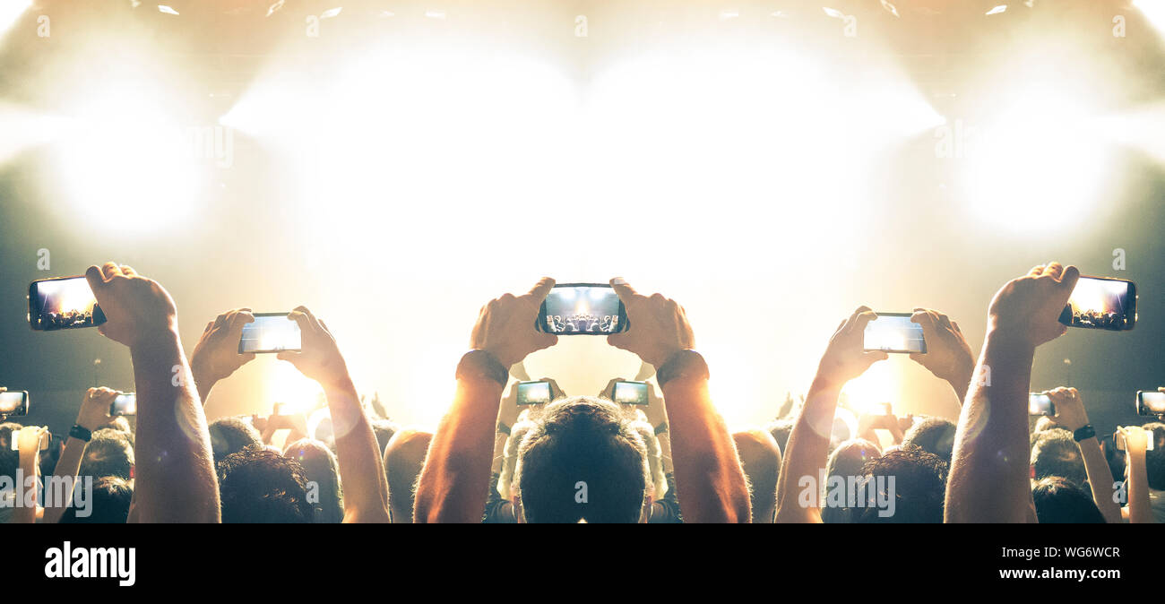 Concert crowd clapping in front of a bright stage Stock Photo - Alamy