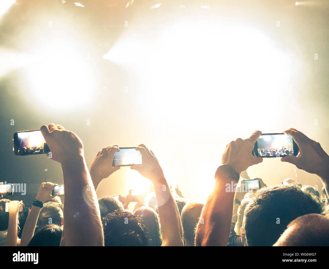 Concert crowd clapping in front of a bright stage Stock Photo - Alamy