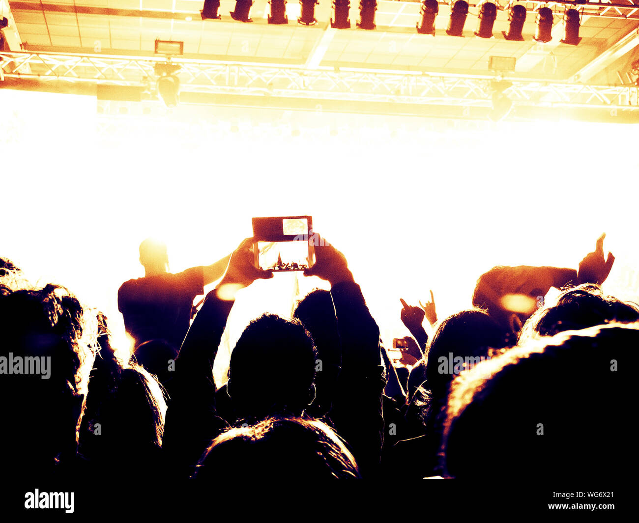 Concert crowd clapping in front of a bright stage Stock Photo - Alamy