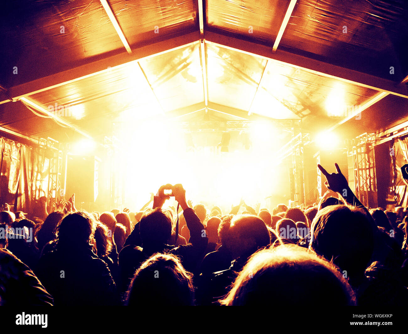 Concert crowd clapping in front of a bright stage Stock Photo - Alamy