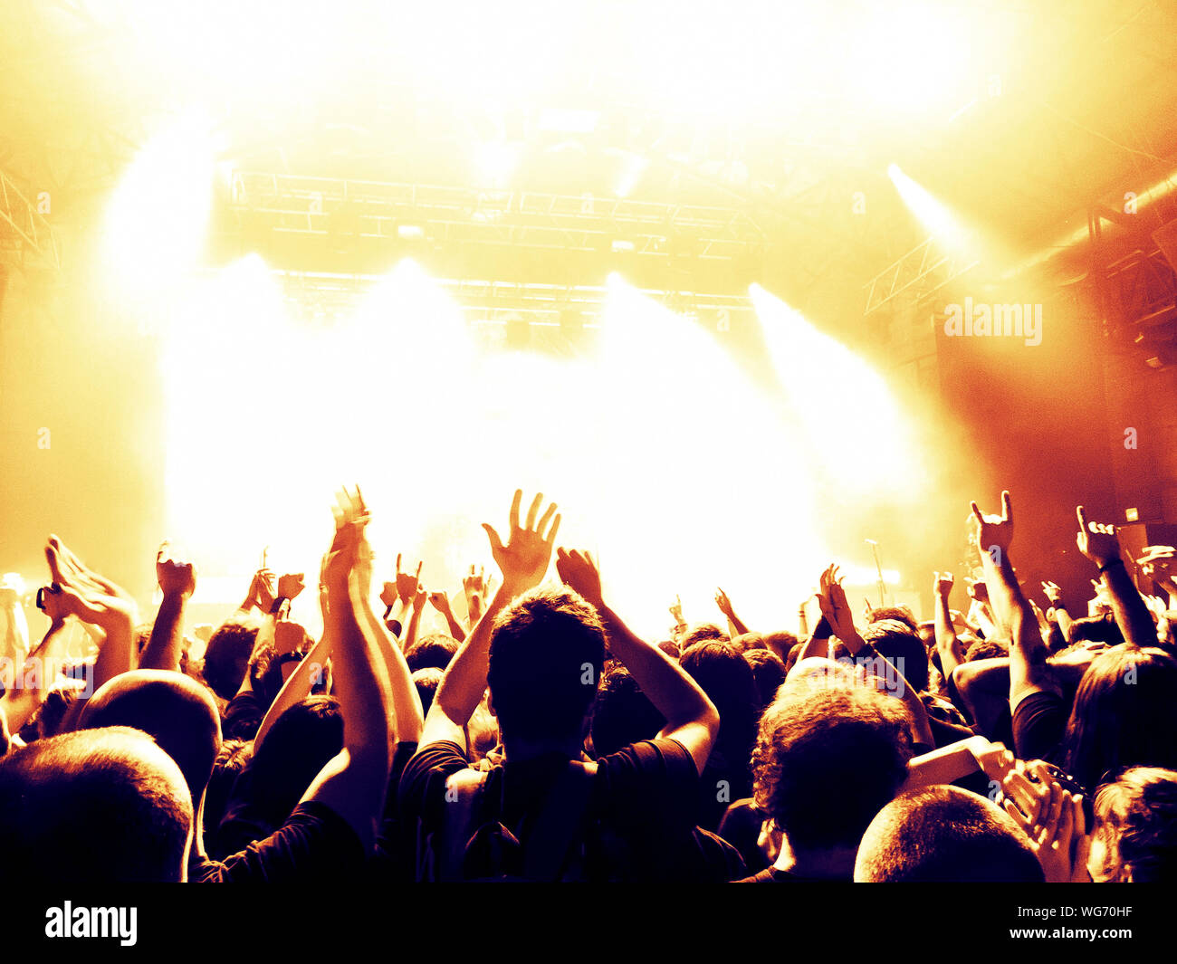 Concert crowd clapping in front of a bright stage Stock Photo - Alamy