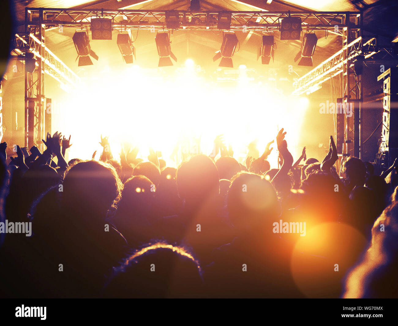 Concert crowd clapping in front of a bright stage Stock Photo - Alamy