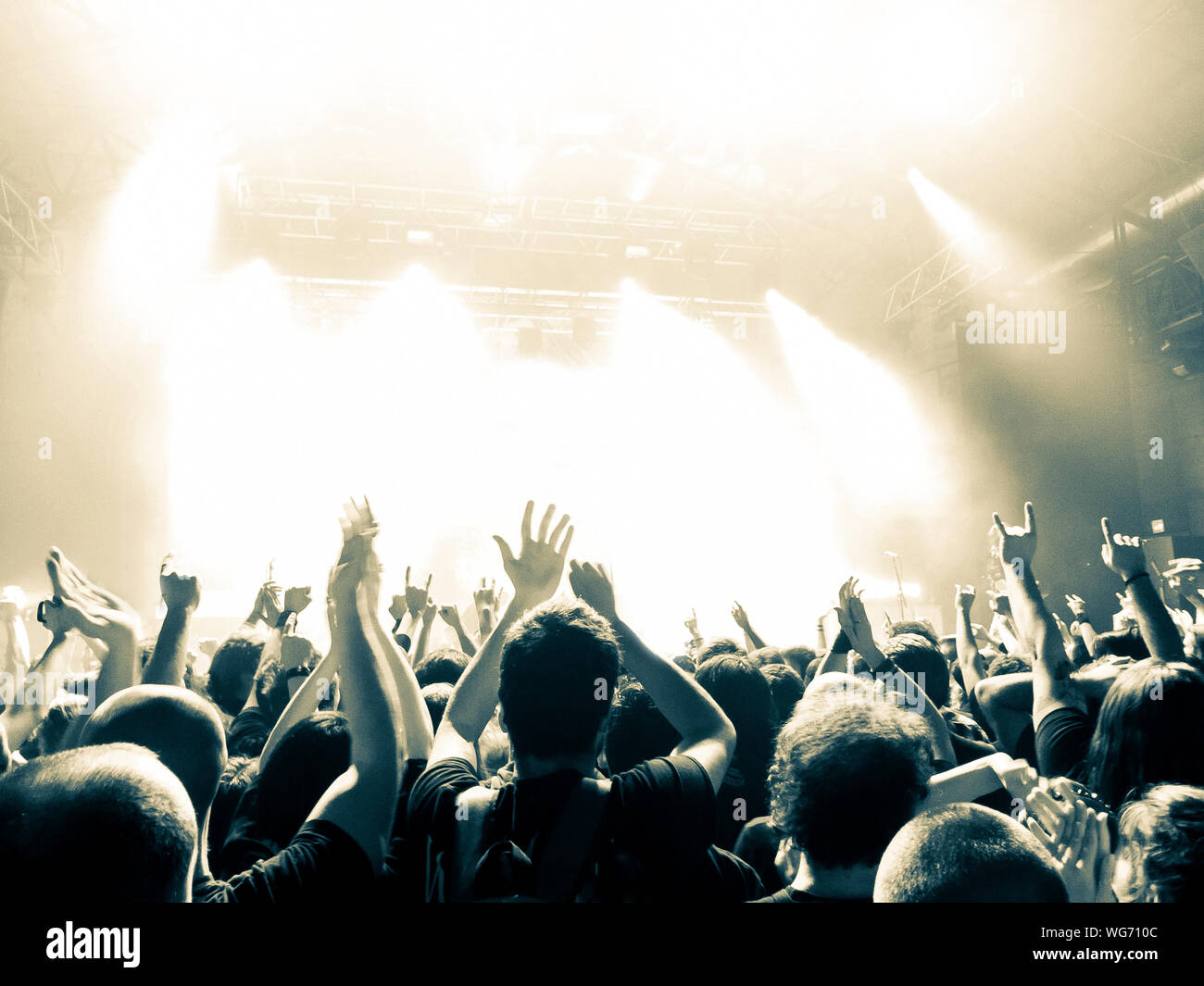 Concert crowd clapping in front of a bright stage Stock Photo - Alamy