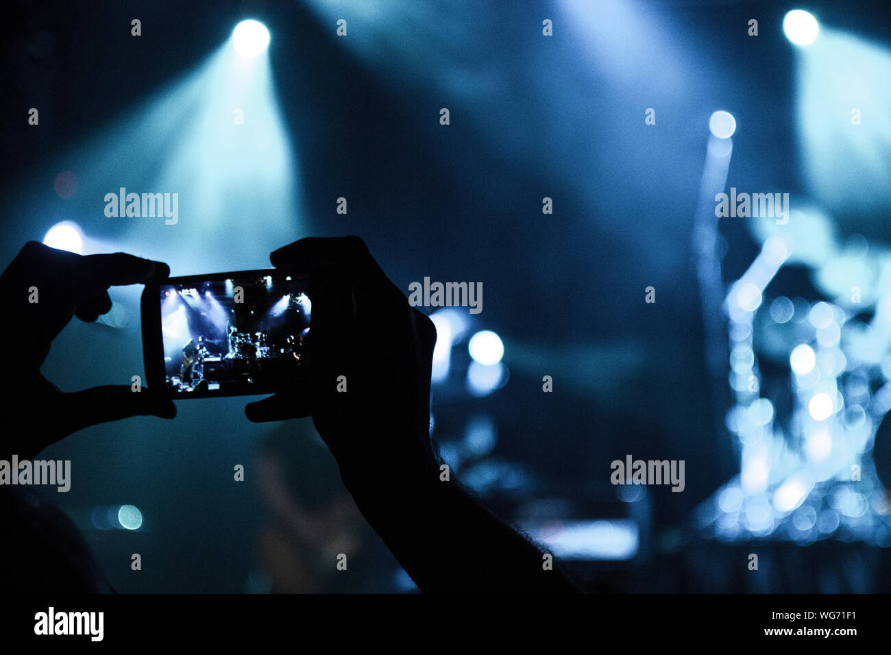 Concert crowd clapping in front of a bright stage Stock Photo - Alamy