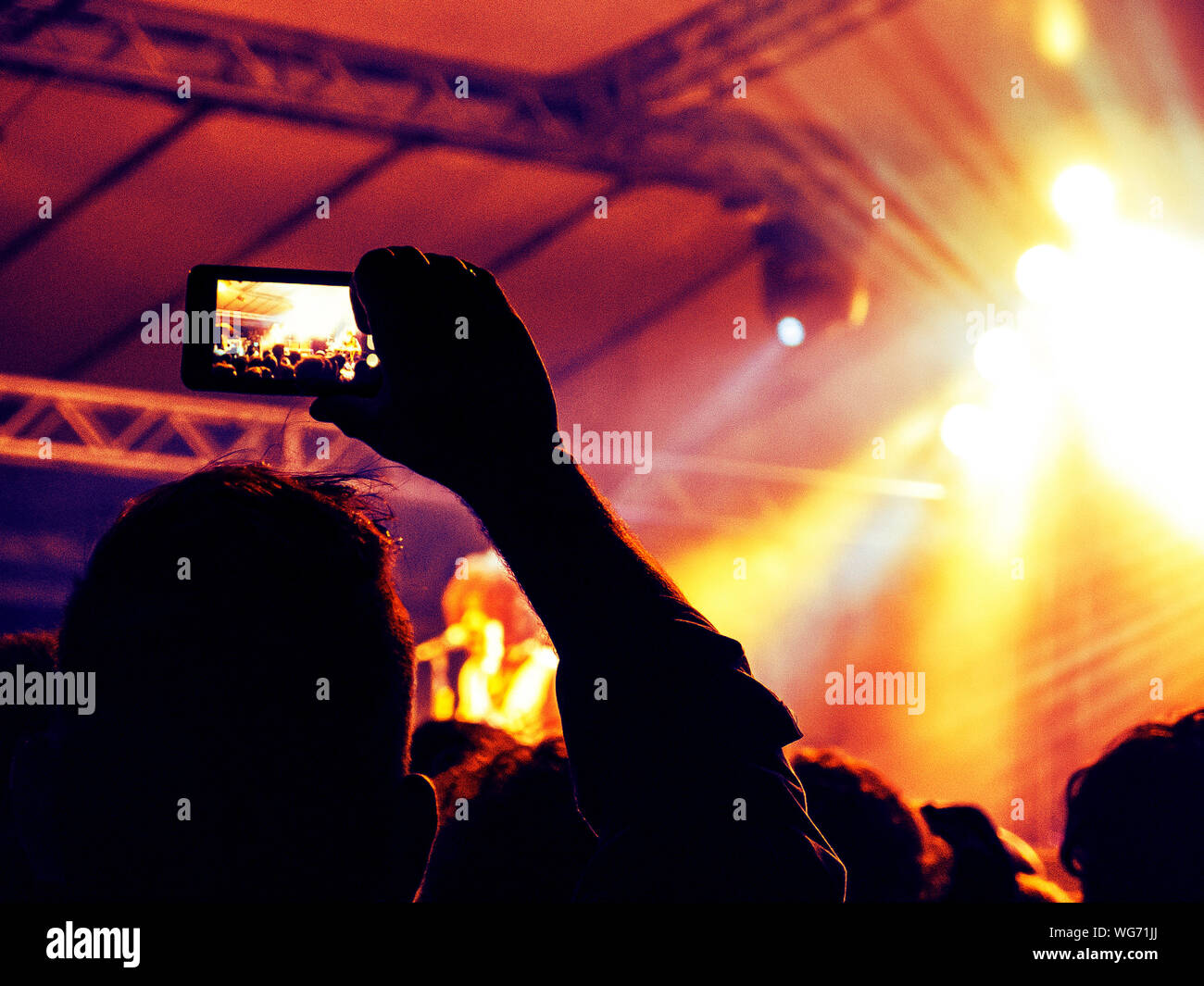 Concert crowd clapping in front of a bright stage Stock Photo - Alamy