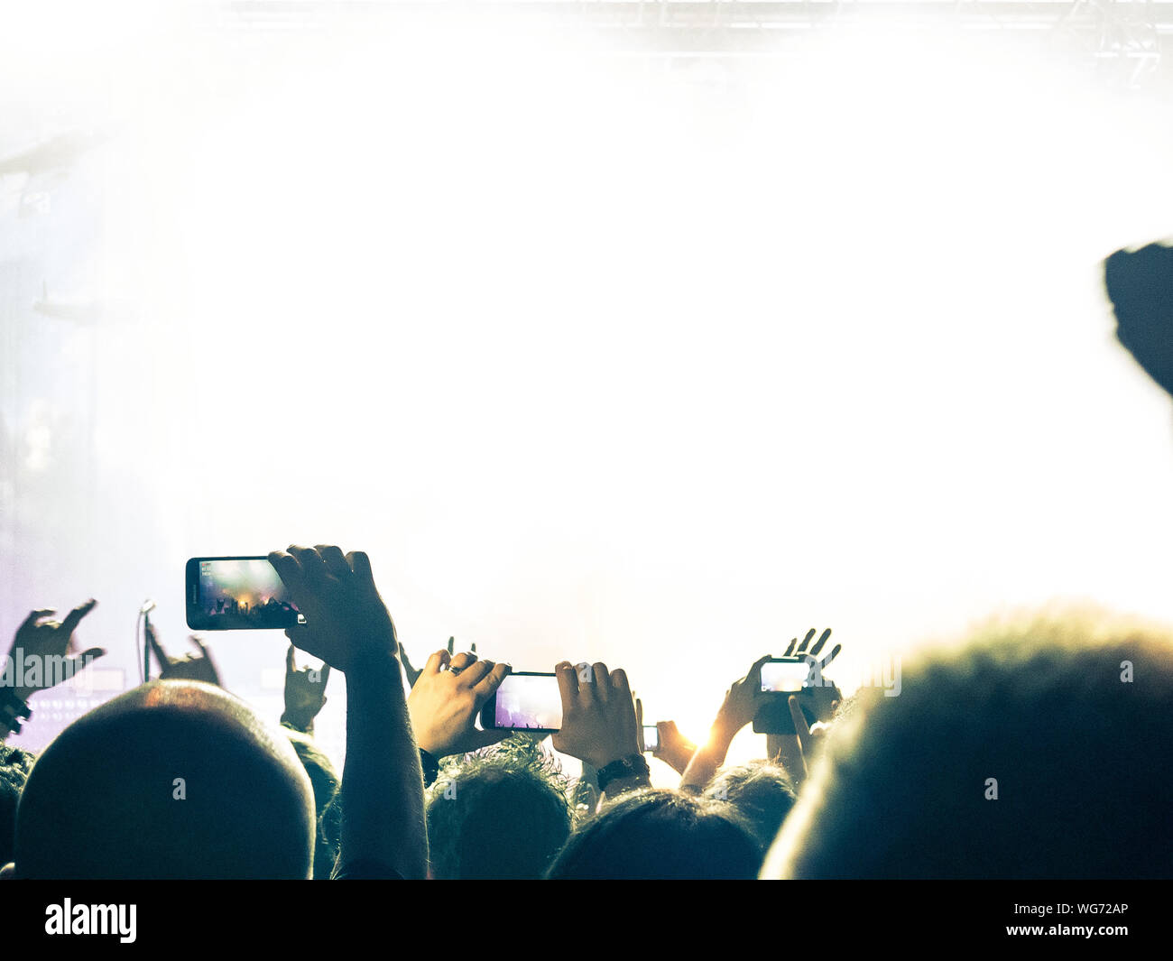 Concert crowd clapping in front of a bright stage Stock Photo - Alamy