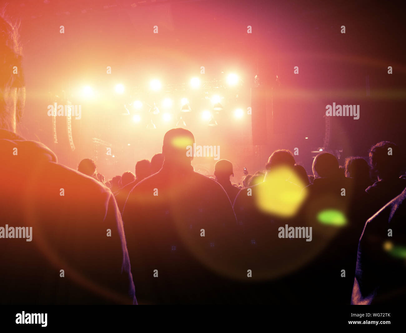 Concert crowd clapping in front of a bright stage Stock Photo - Alamy